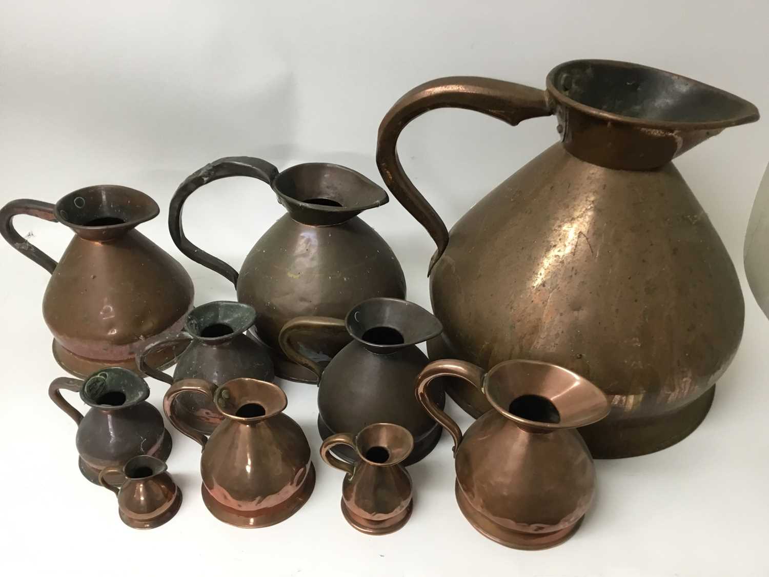 Lot 405 - Matched set of nine antique brass flagon